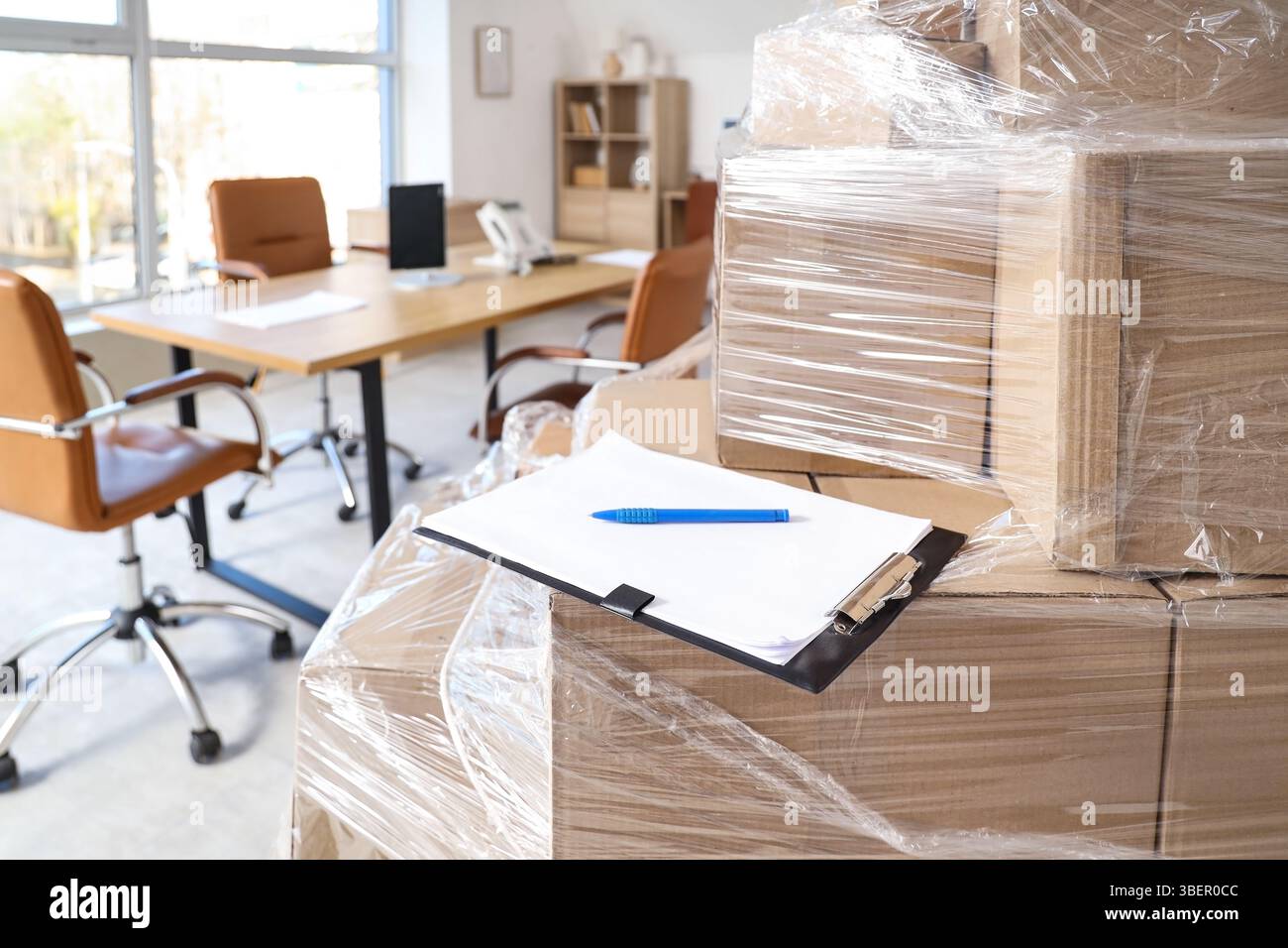 Wrapped cardboard boxes with stretch film and clipboard in office on ...