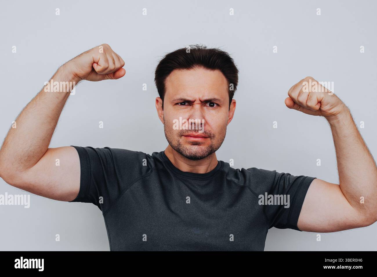 Strong man posing on white wall background Stock Photo - Alamy