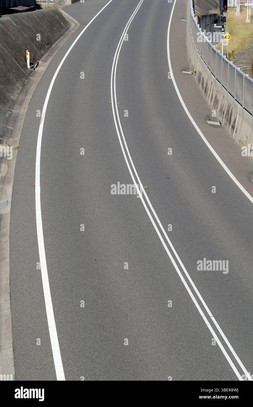 Curved asphalt bitumen road with white lane markings and concrete ...