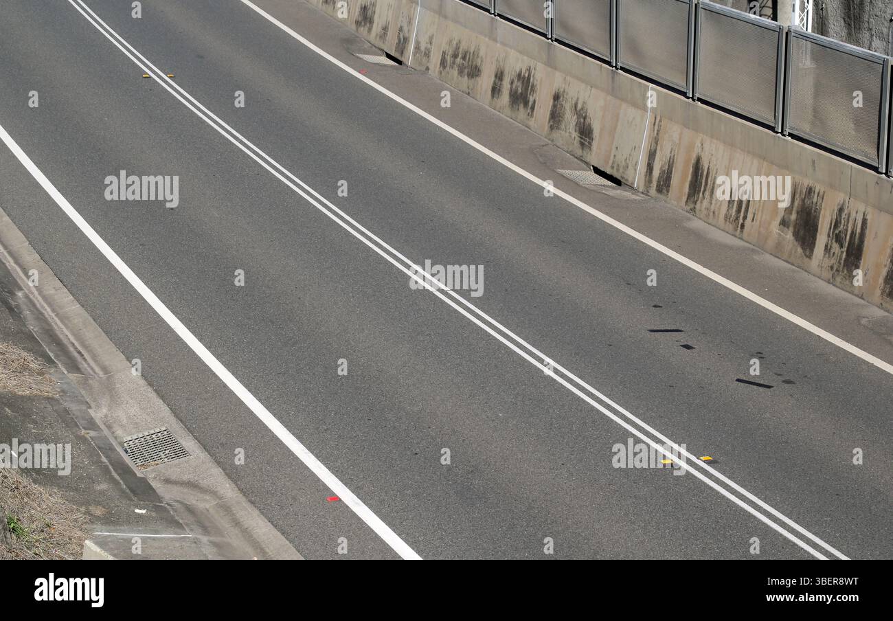 Two-lane asphalt bitumen road with white lane markings and a concrete ...