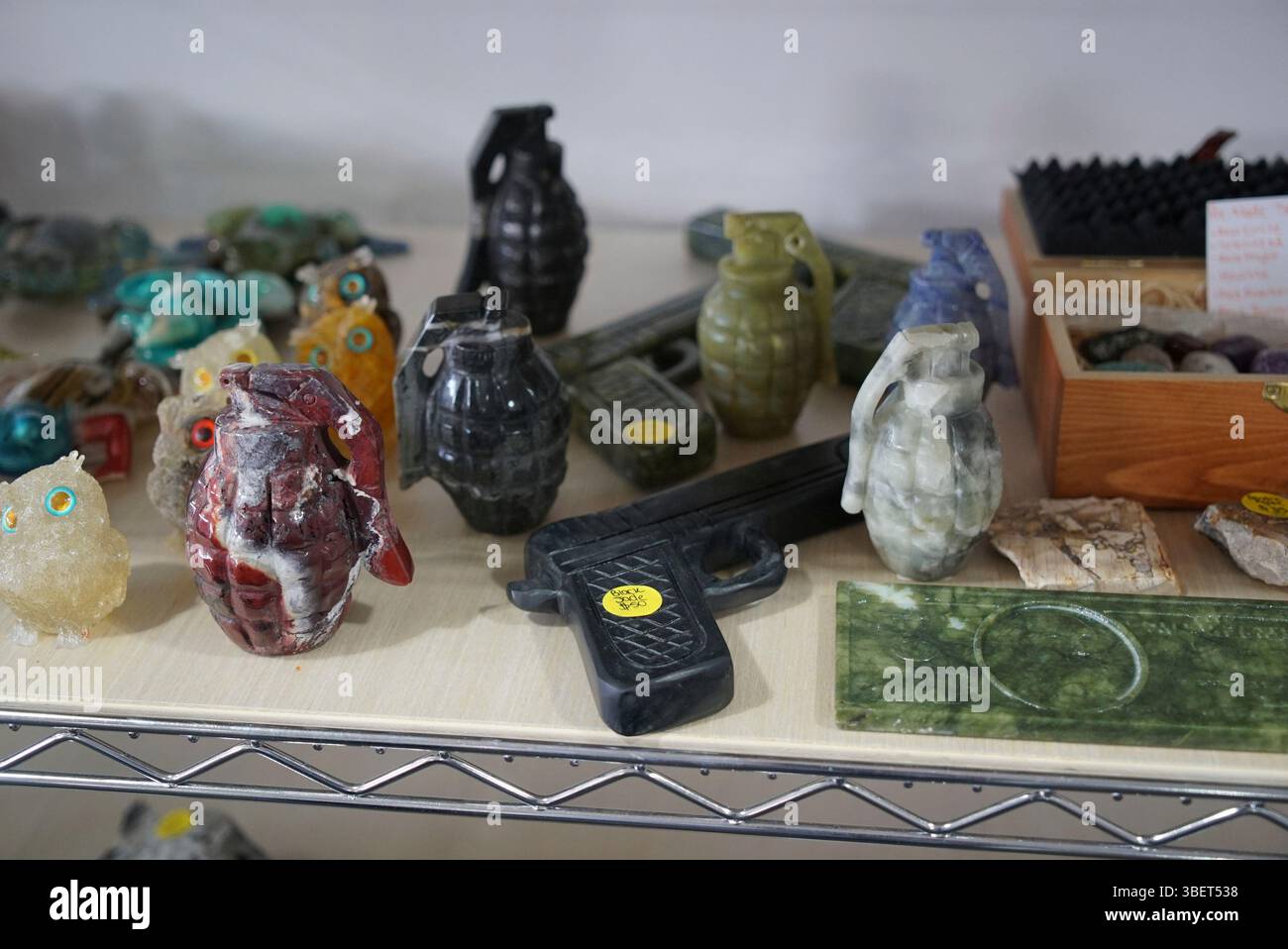 Stones in the shape of pistols and hand grenades sit on a shelf at ...