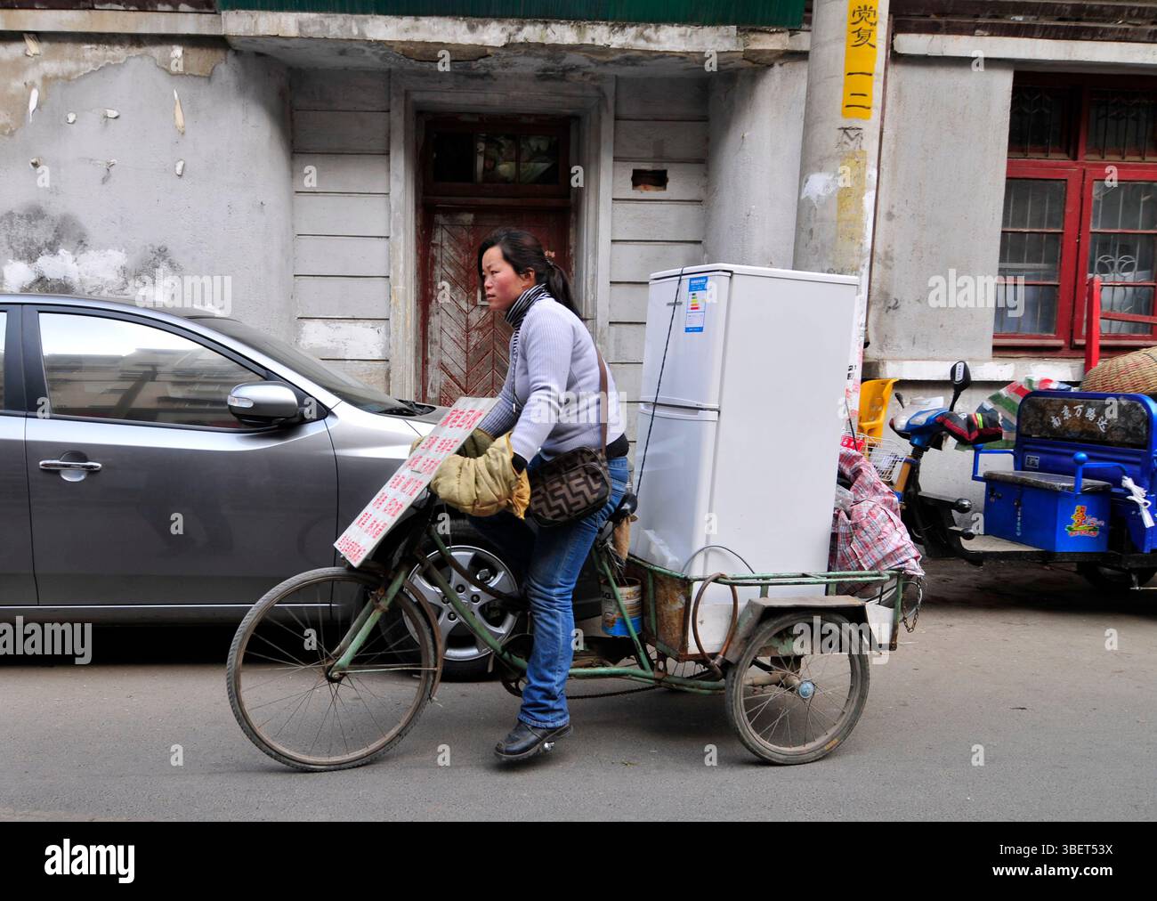 A woman transporting a refrigerator on her tricycle in Nanjing, China ...