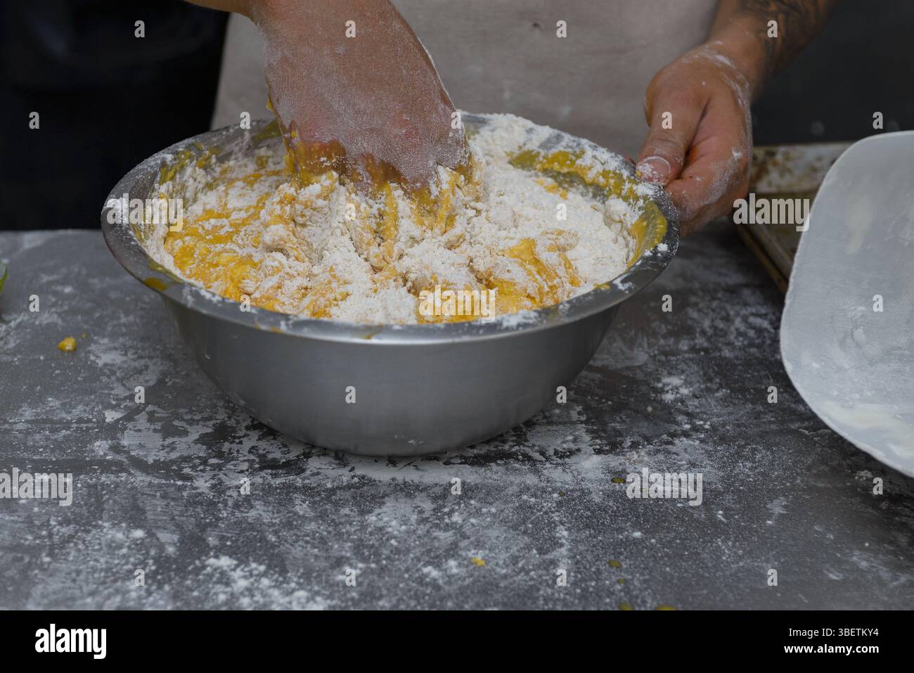 A baker hand mixing flour and eggs in a metal bowl Stock Photo - Alamy