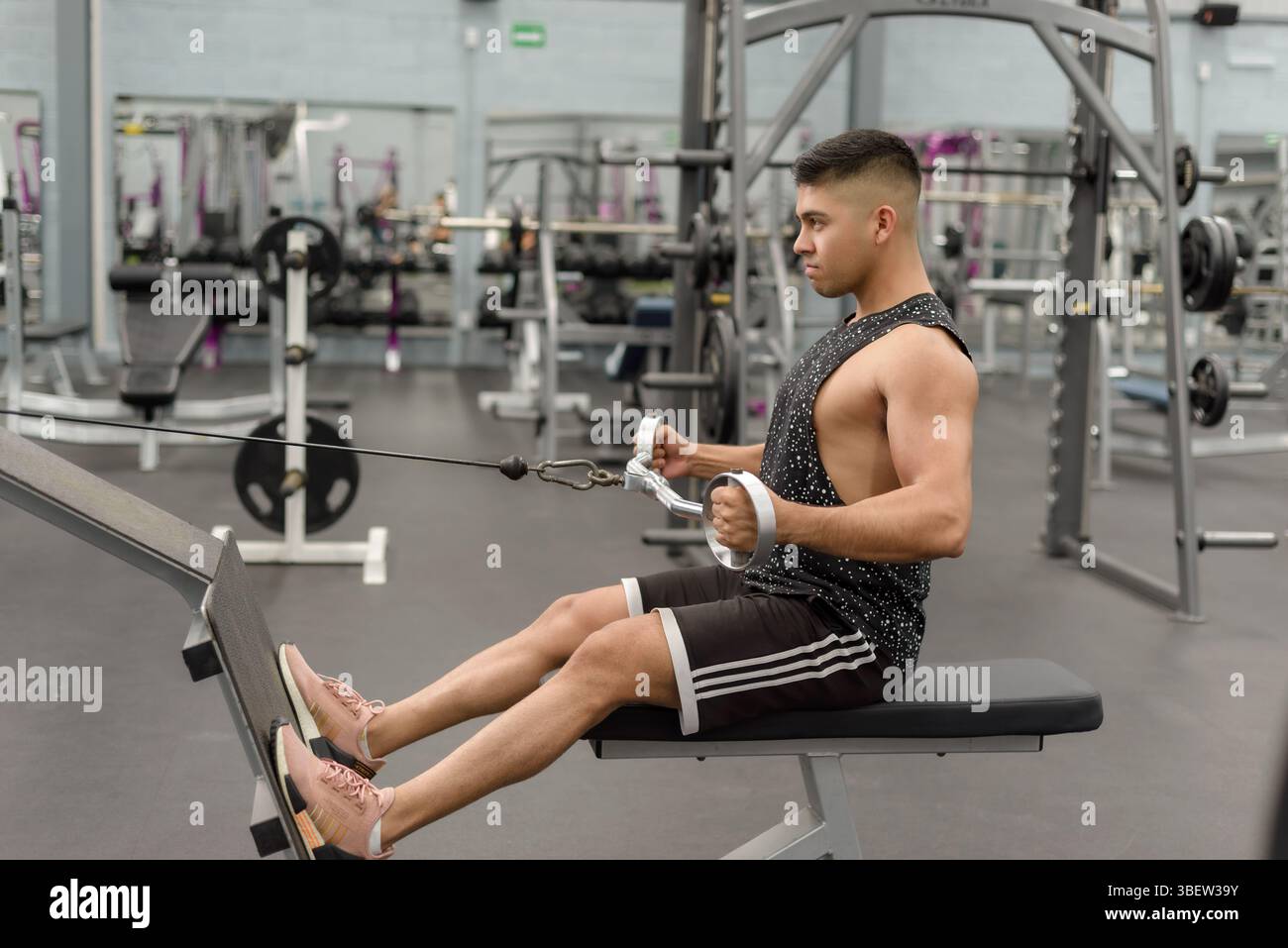 A young man intensely focuses on a seated cable row exercise in a well ...