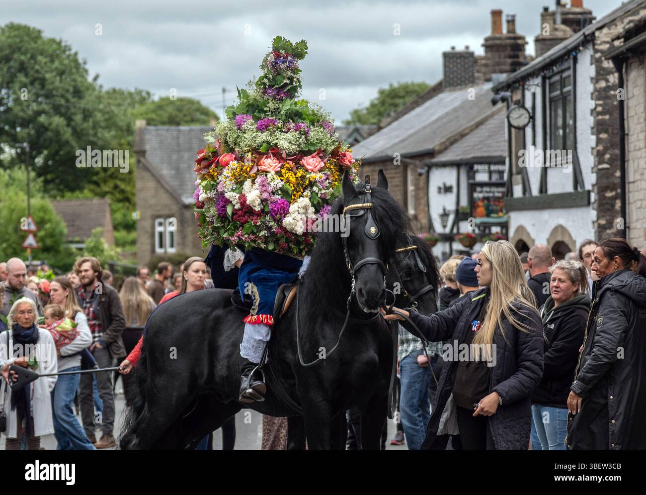 The ceremonial king, wears a large flower-covered framework while ...