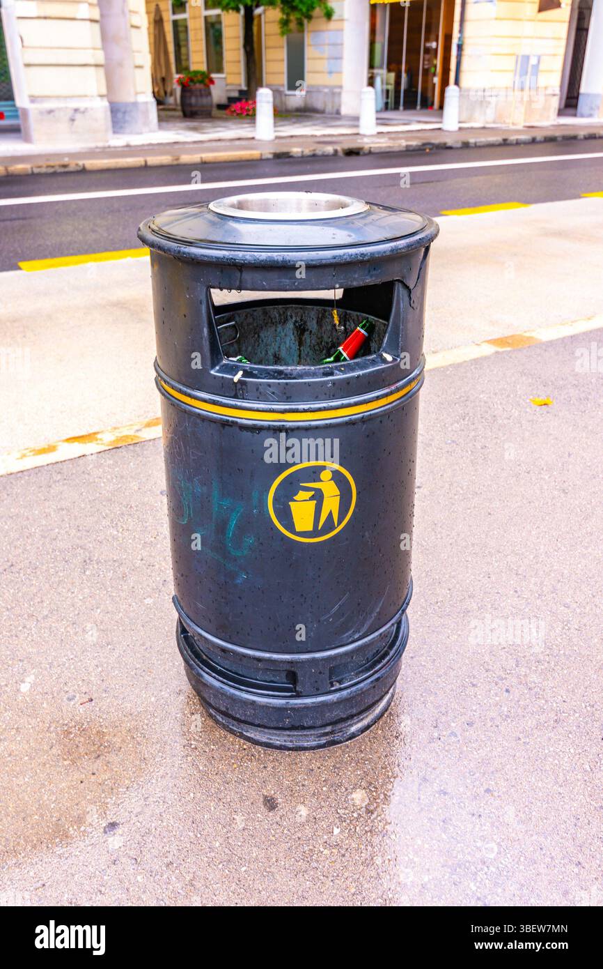 Trash bin with garbage inside in city street. Black recycle bin on the ...