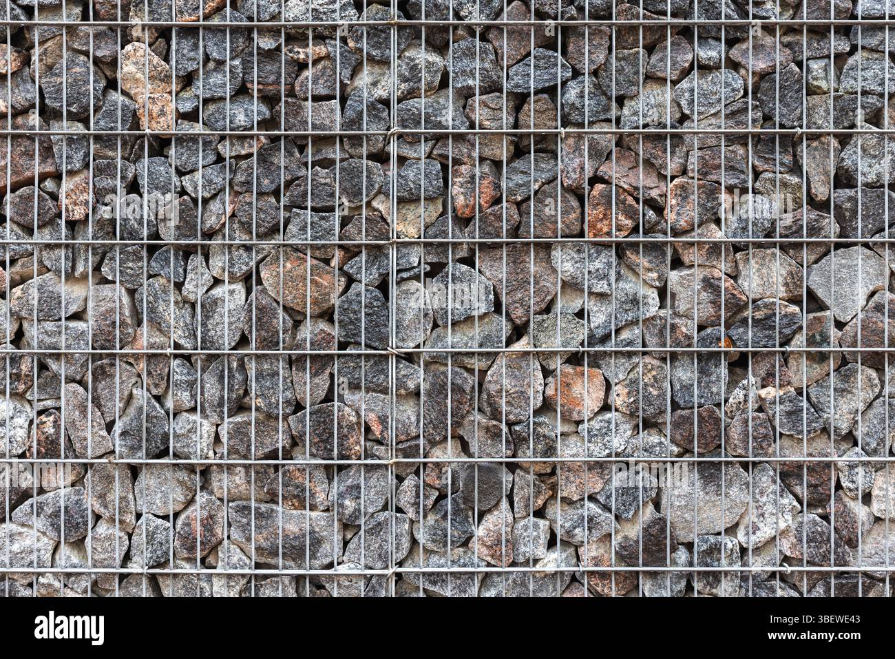 Close-up view of a metal wire fence frame filled with rocks ...