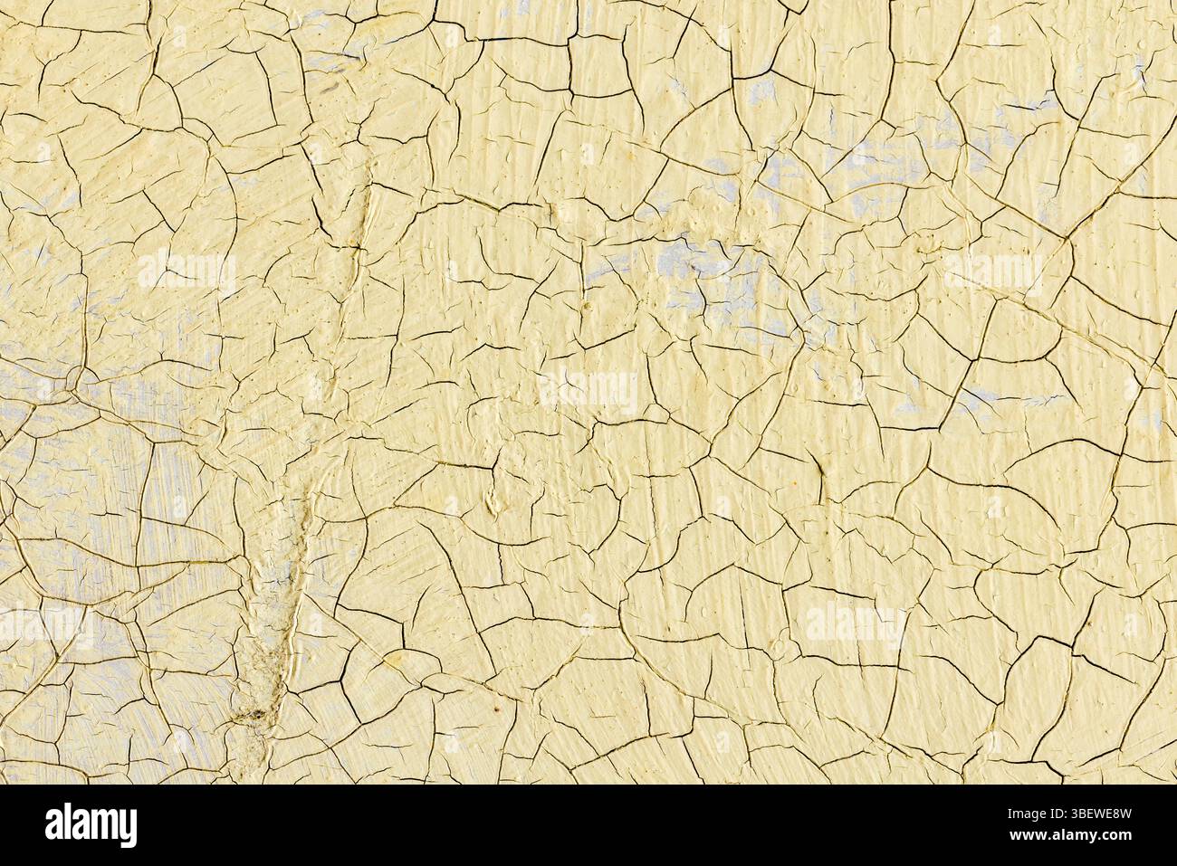 Close-up view of cracked yellow paint revealing a textured surface ...