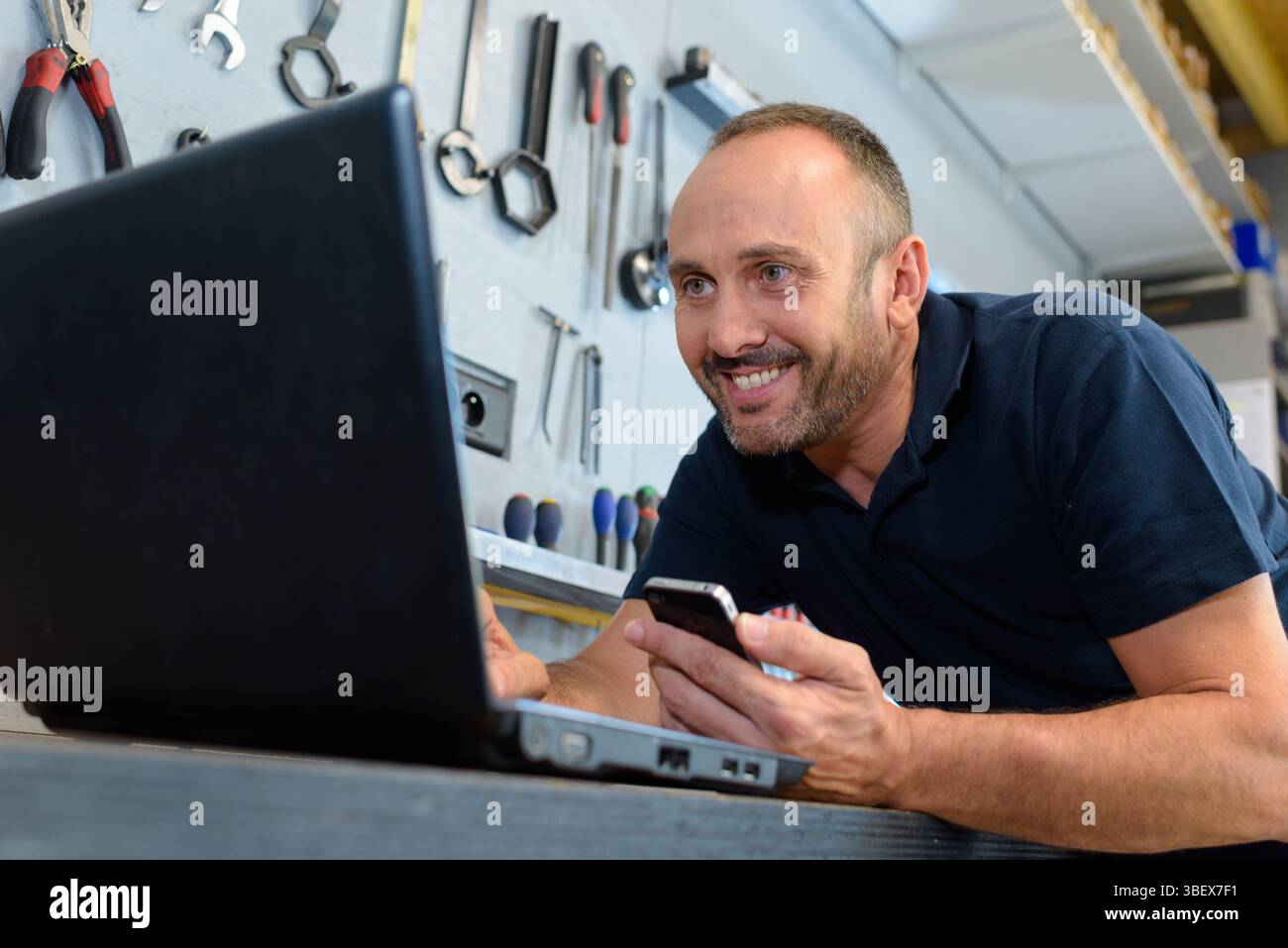 workman laughing facing the laptop Stock Photo - Alamy