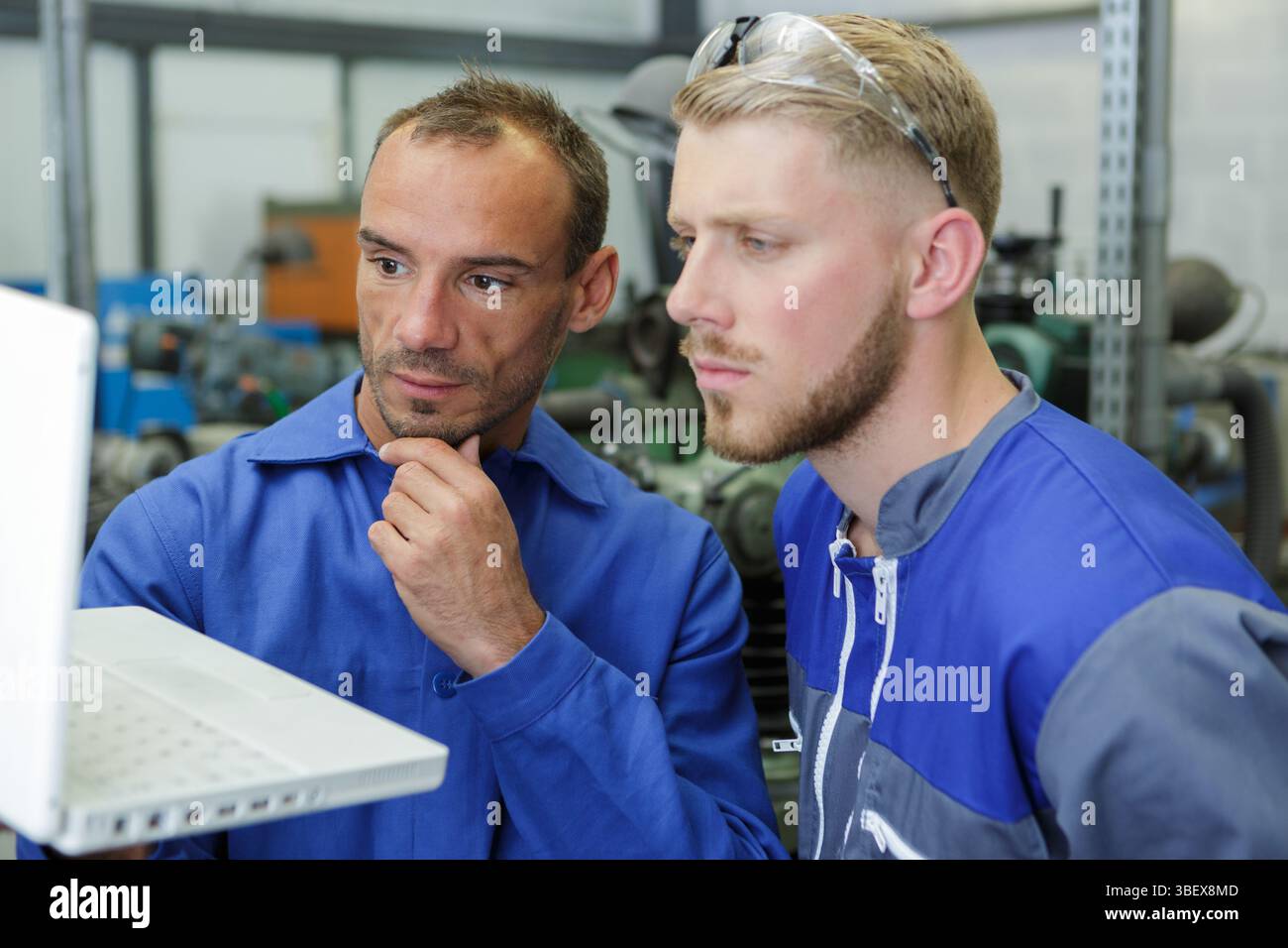 two male engineers wearing overalls looking at laptop computer Stock ...