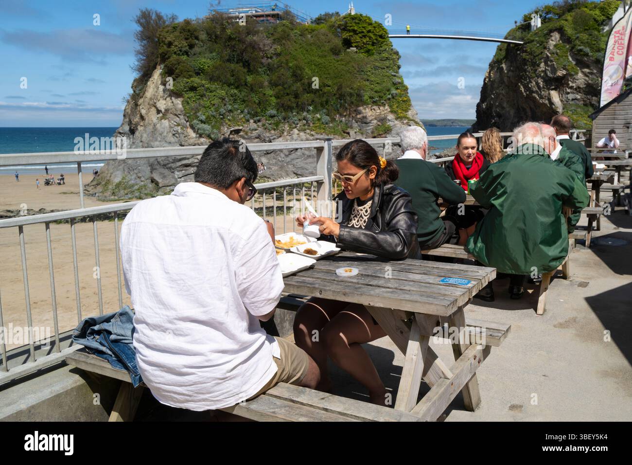 Holidaymakers sitting and eating food on the promenade at Towan Beach ...