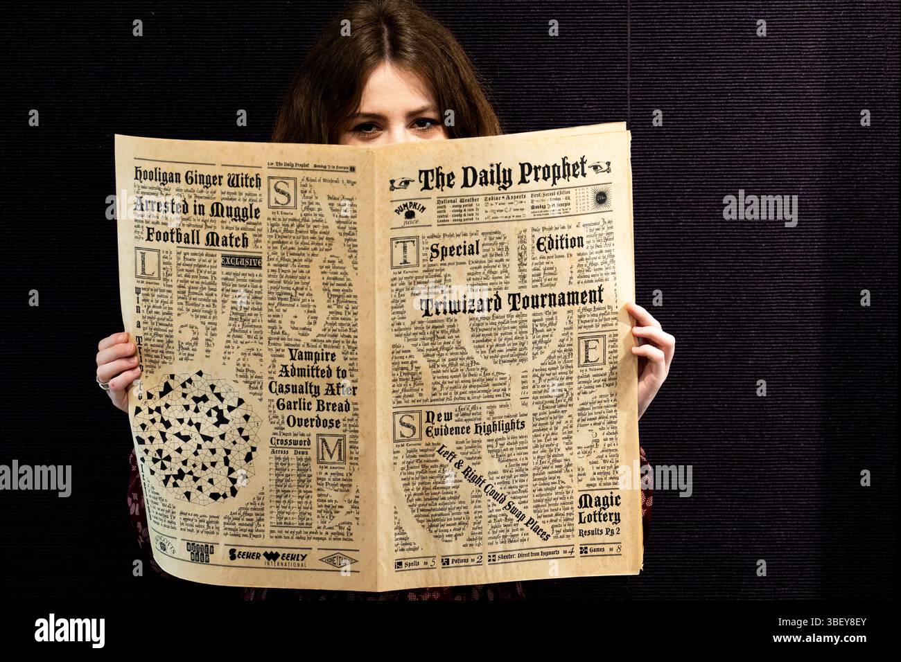 A member of staff looks at The Daily Prophet prop newspaper titled ...