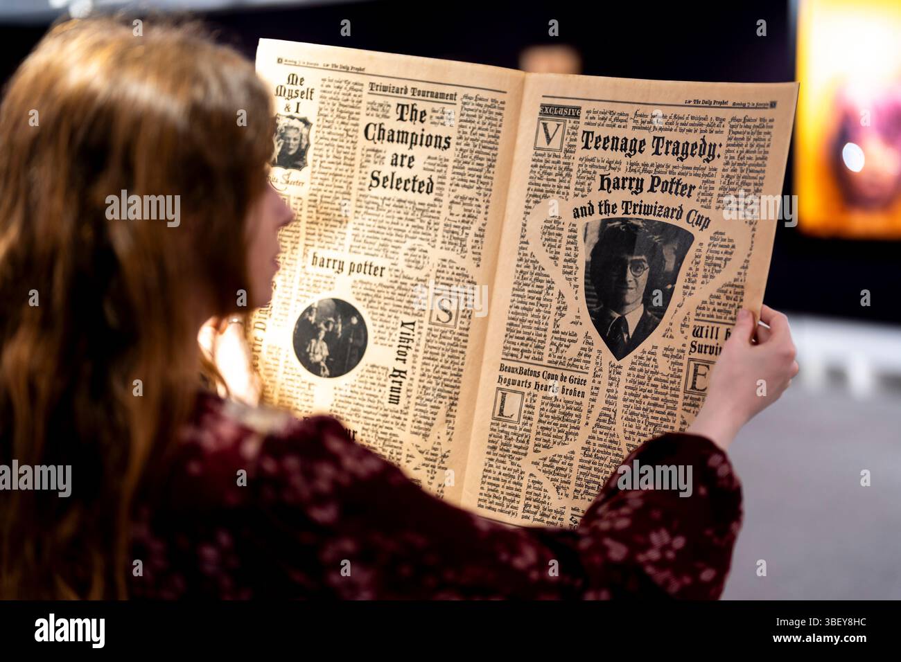 A member of staff looks at The Daily Prophet prop newspaper titled ...