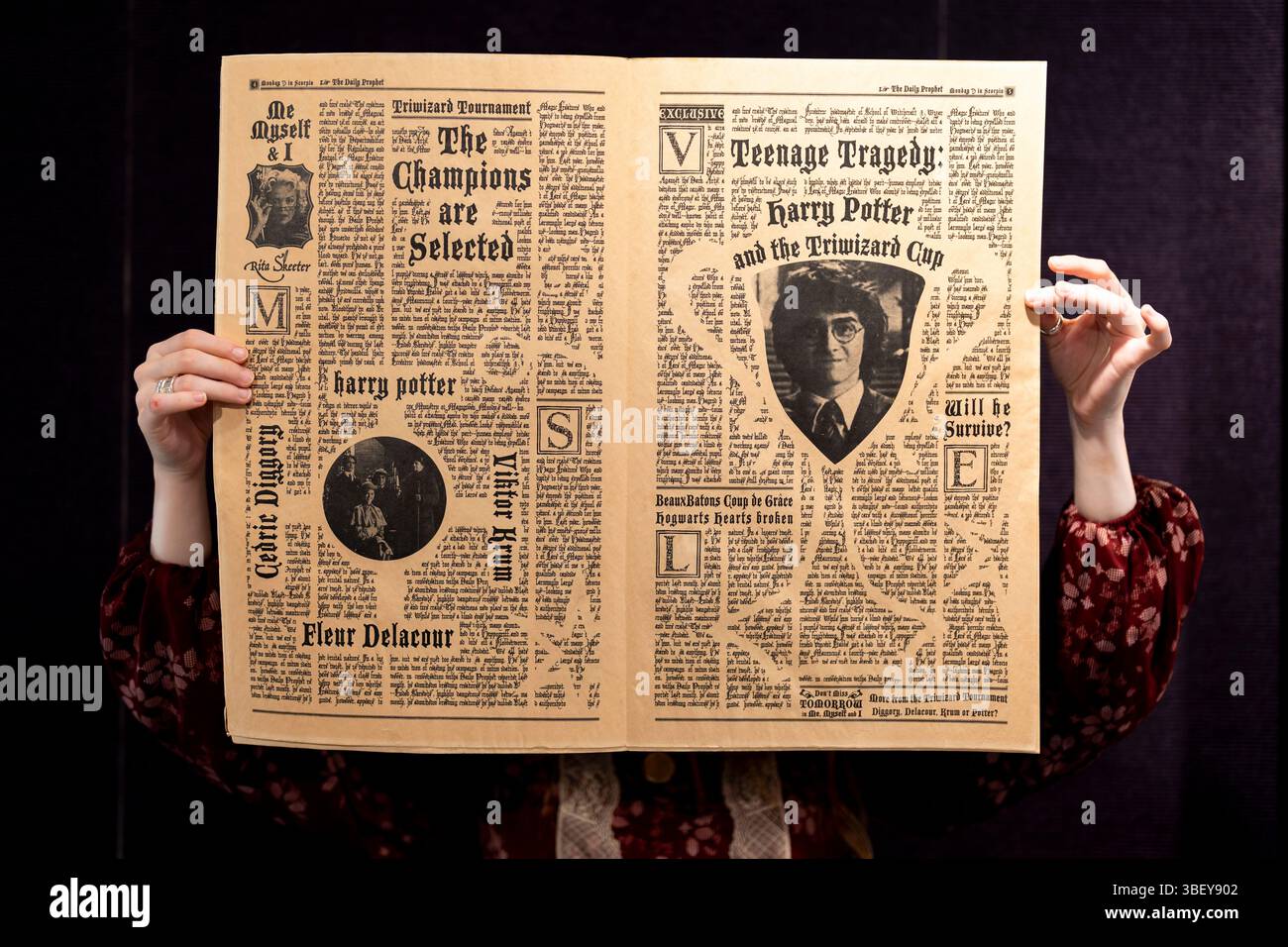 A member of staff looks at The Daily Prophet prop newspaper titled ...