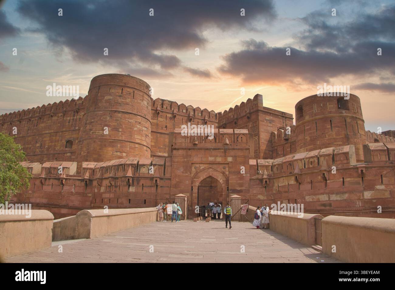 Agra Fort at sunset with tourists entering the massive red sandstone ...