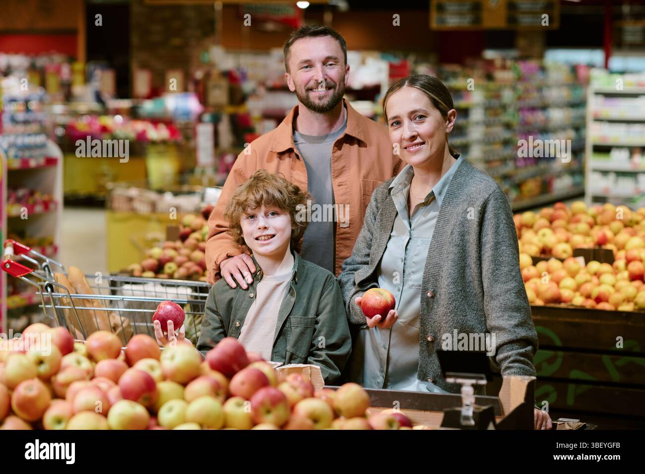 Family buying fresh apples at grocery store, standing by produce ...