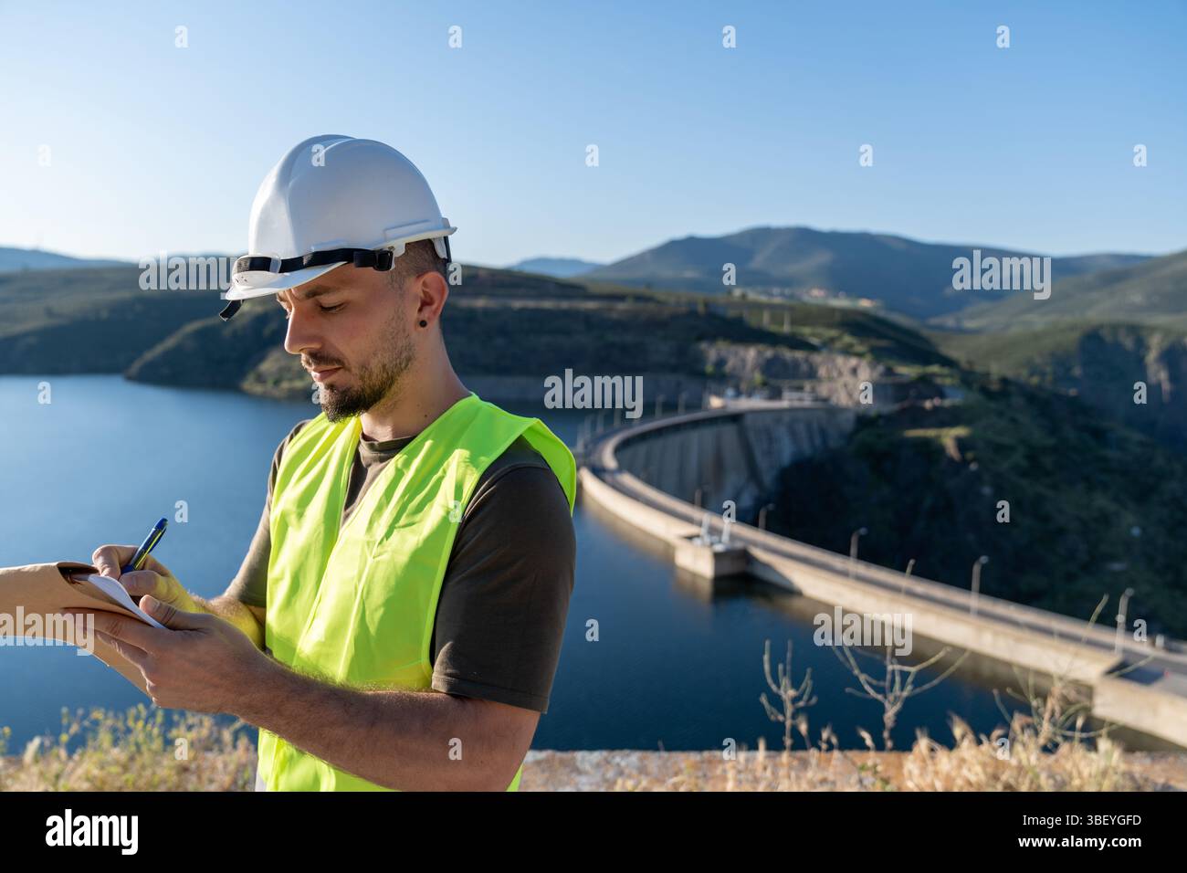 Engineer taking notes near a dam and reservoir Stock Photo - Alamy