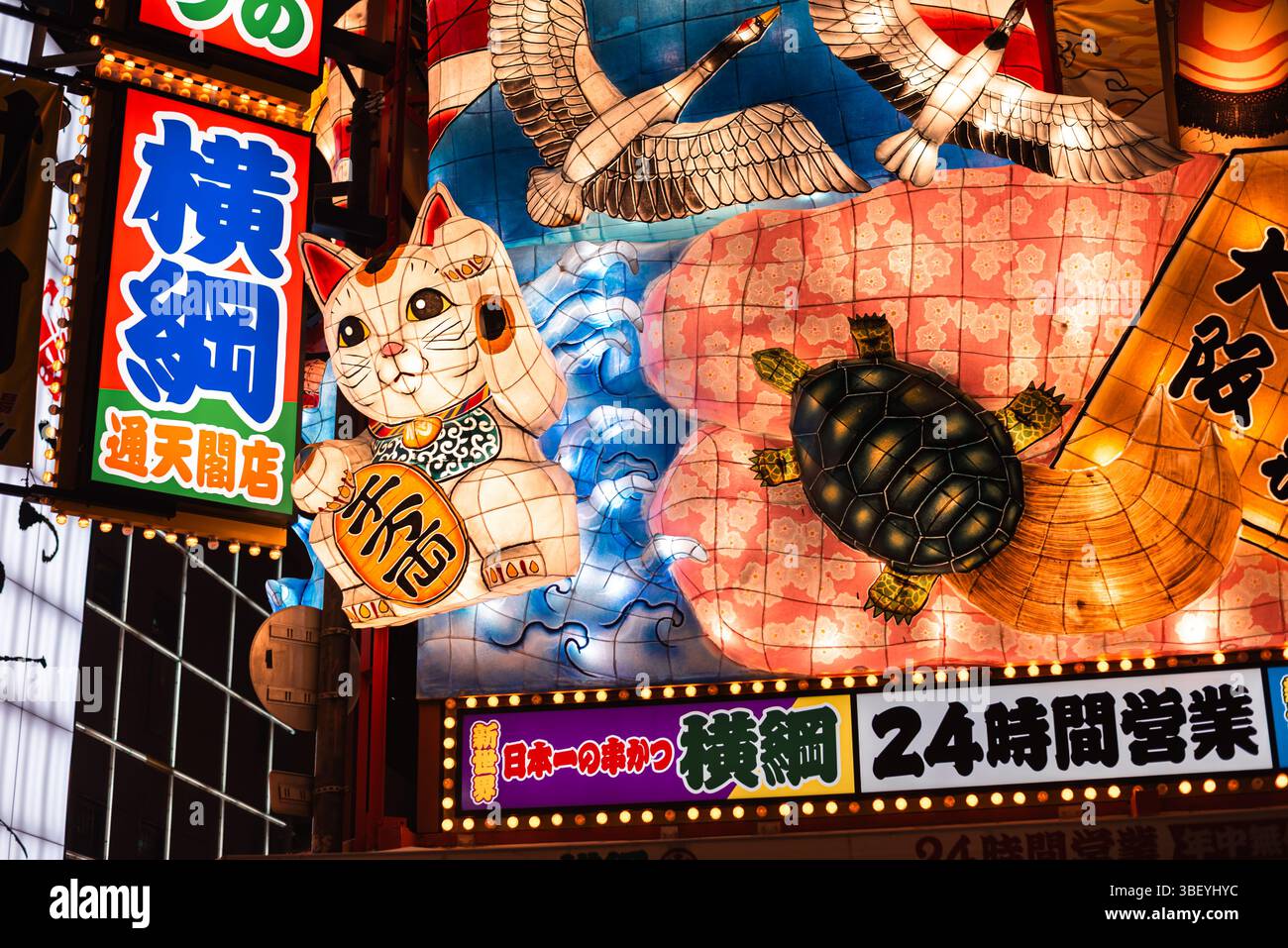 A vibrant, illuminated Japanese signboard featuring a lucky cat, turtle ...