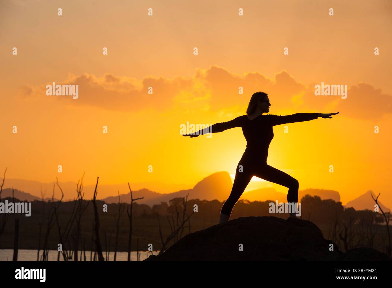 Young woman practising yoga posture by the Senanayake Samudraya Lake at ...
