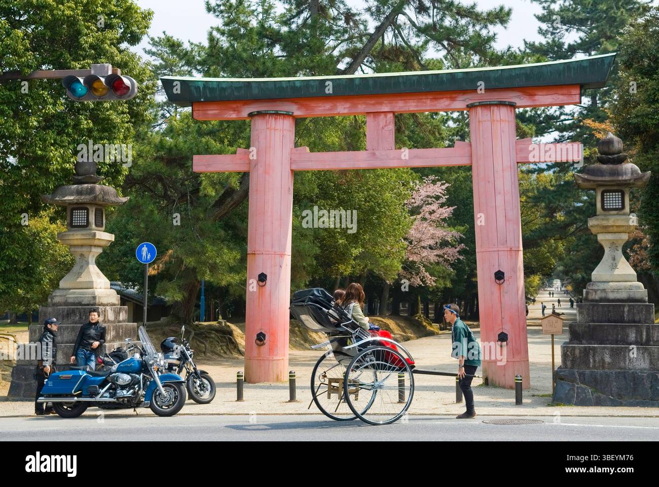 Tourist pulled rickshaw and motorcycles in fronr a torii at Kasuga ...