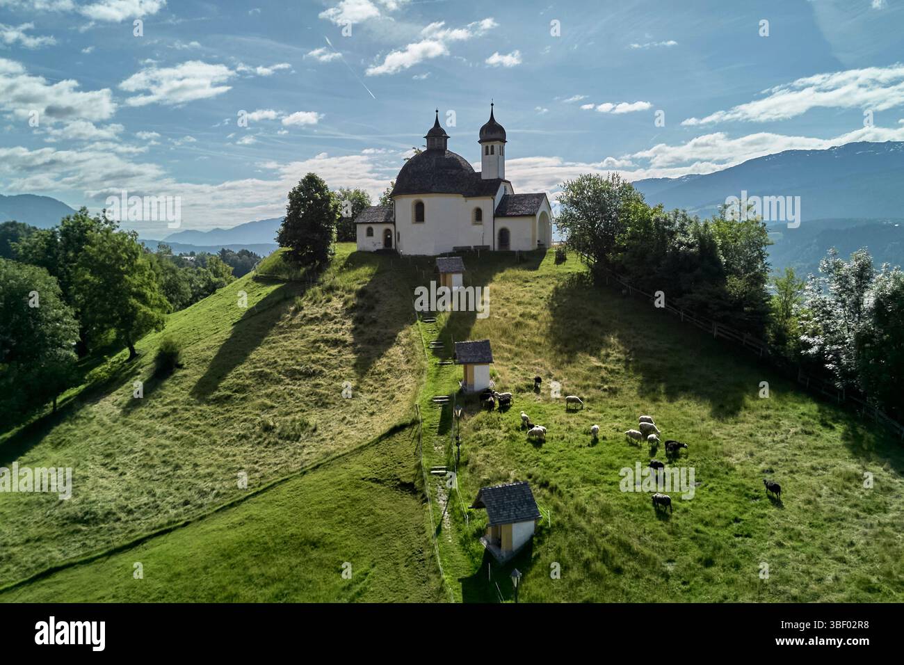 Sheep graze on a meadow under the Kalvarienberg chapel in the outskirts ...