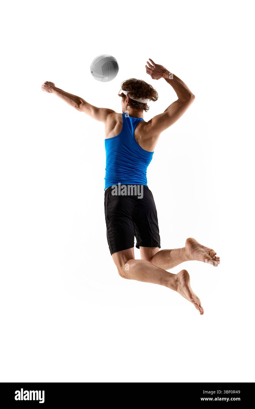 Back view of volleyball player jumping to hit ball in active motion ...