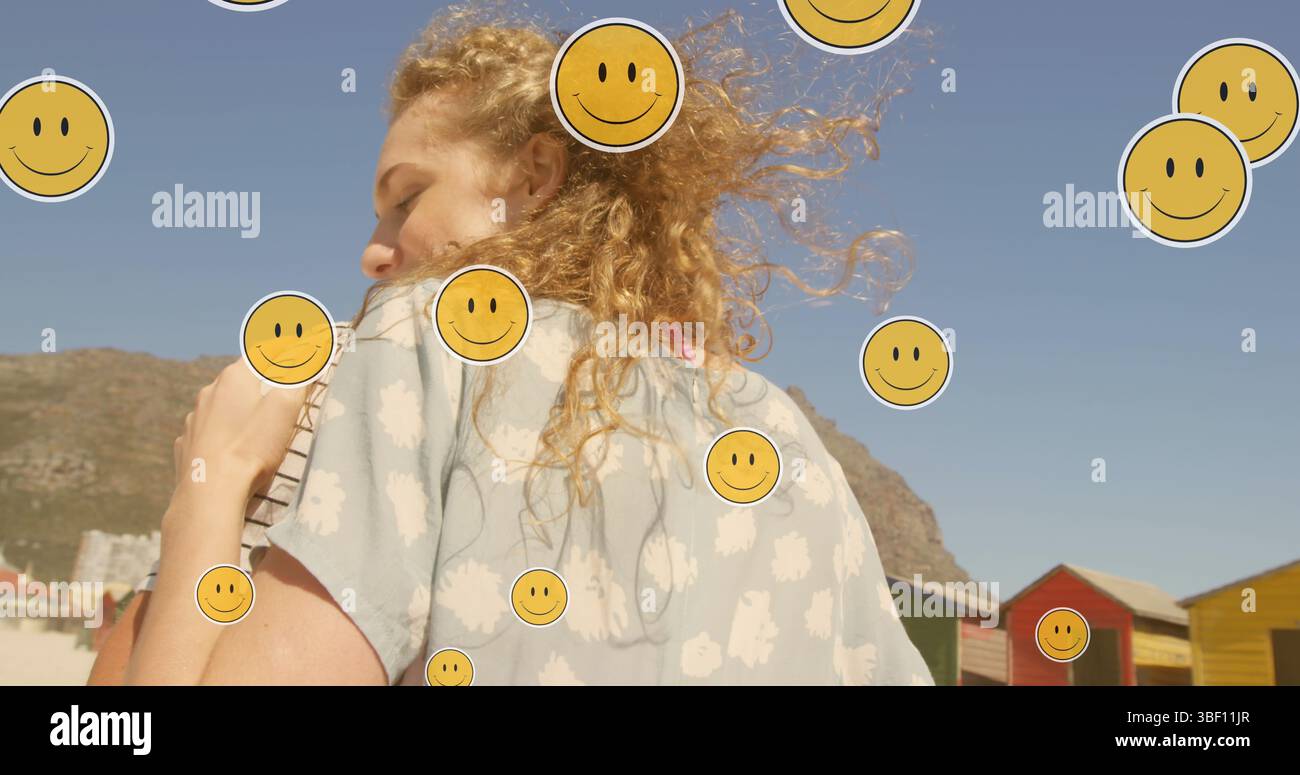 Image of emoji icons over happy caucasian couple embracing at beach ...
