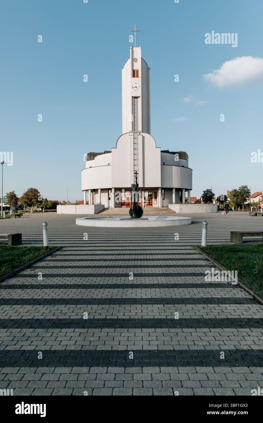 A modern church with a tall, rectangular steeple and a circular base. A ...