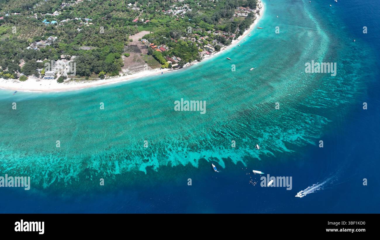 A aerial of a coral cay island surrounded by shallow reef and deep blue ...
