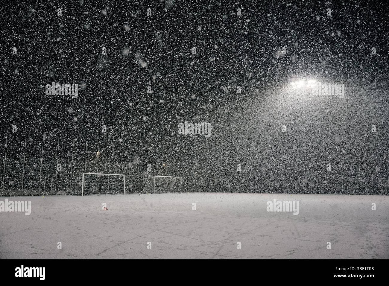 Snow falling on soccer field at night under stadium lights Stock Photo ...