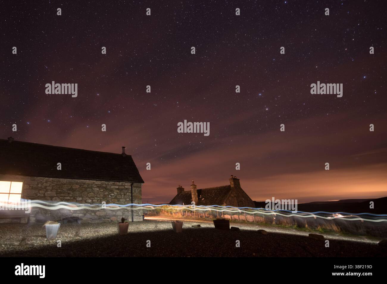 A scottish landscape at night with lights in the sky in the distance ...