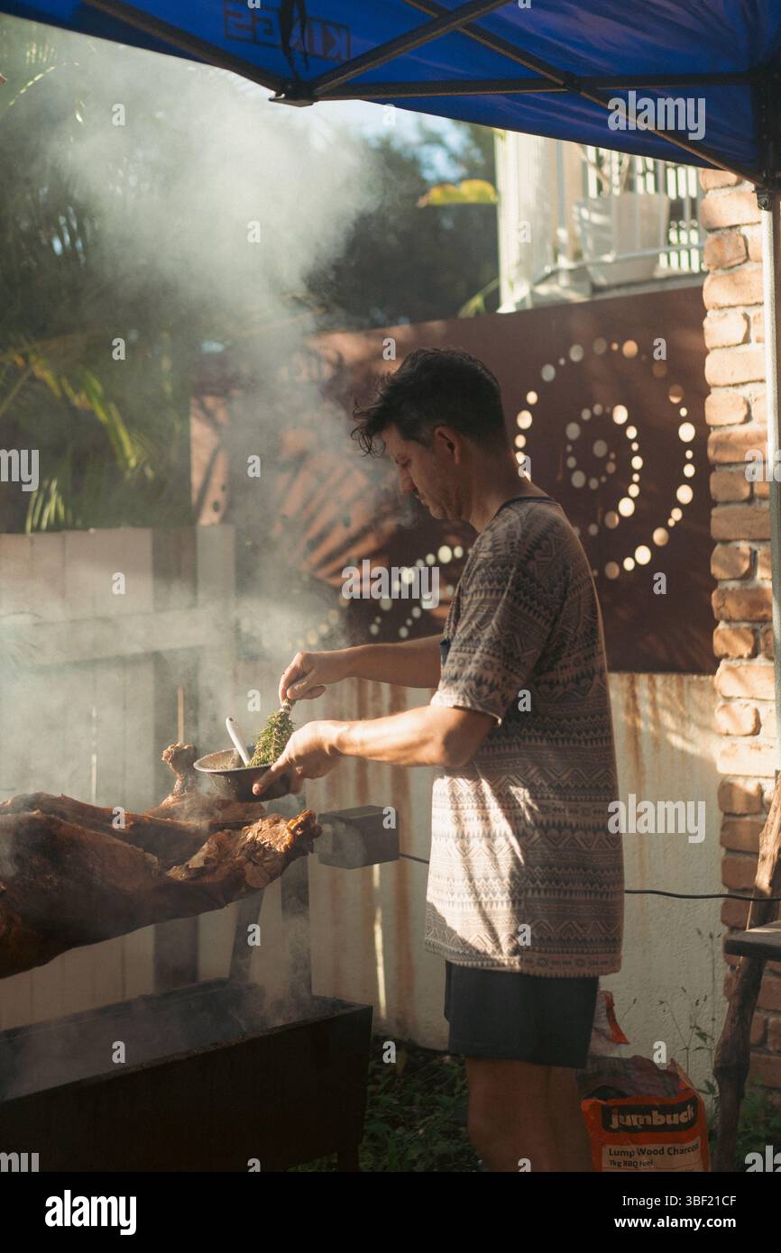 Man grilling meat outdoors under smoky sunlight Stock Photo - Alamy