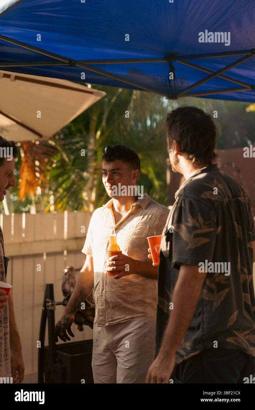 Backyard gathering under the sun, friends sharing drinks Stock Photo ...