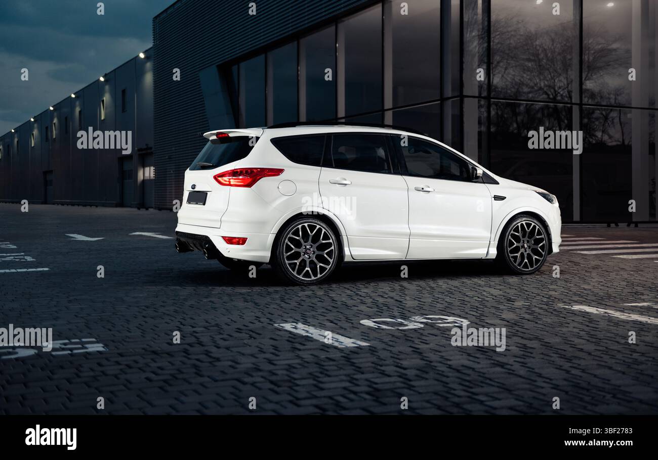 white Ford Kuga SUV in cobbled parking lot at dusk - side view. Long ...