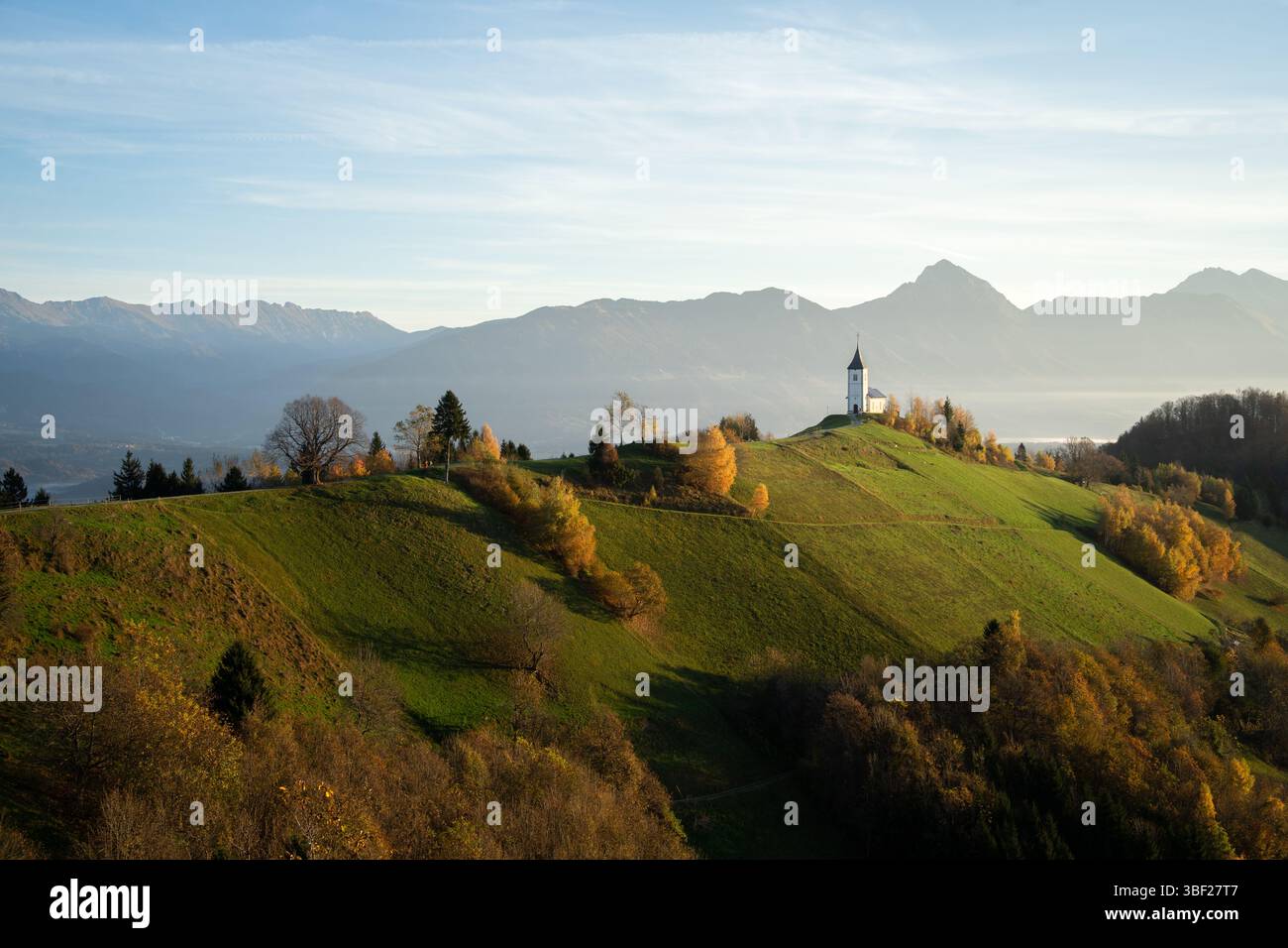 Picturesque alpine landscape with small church on top of a hill and ...
