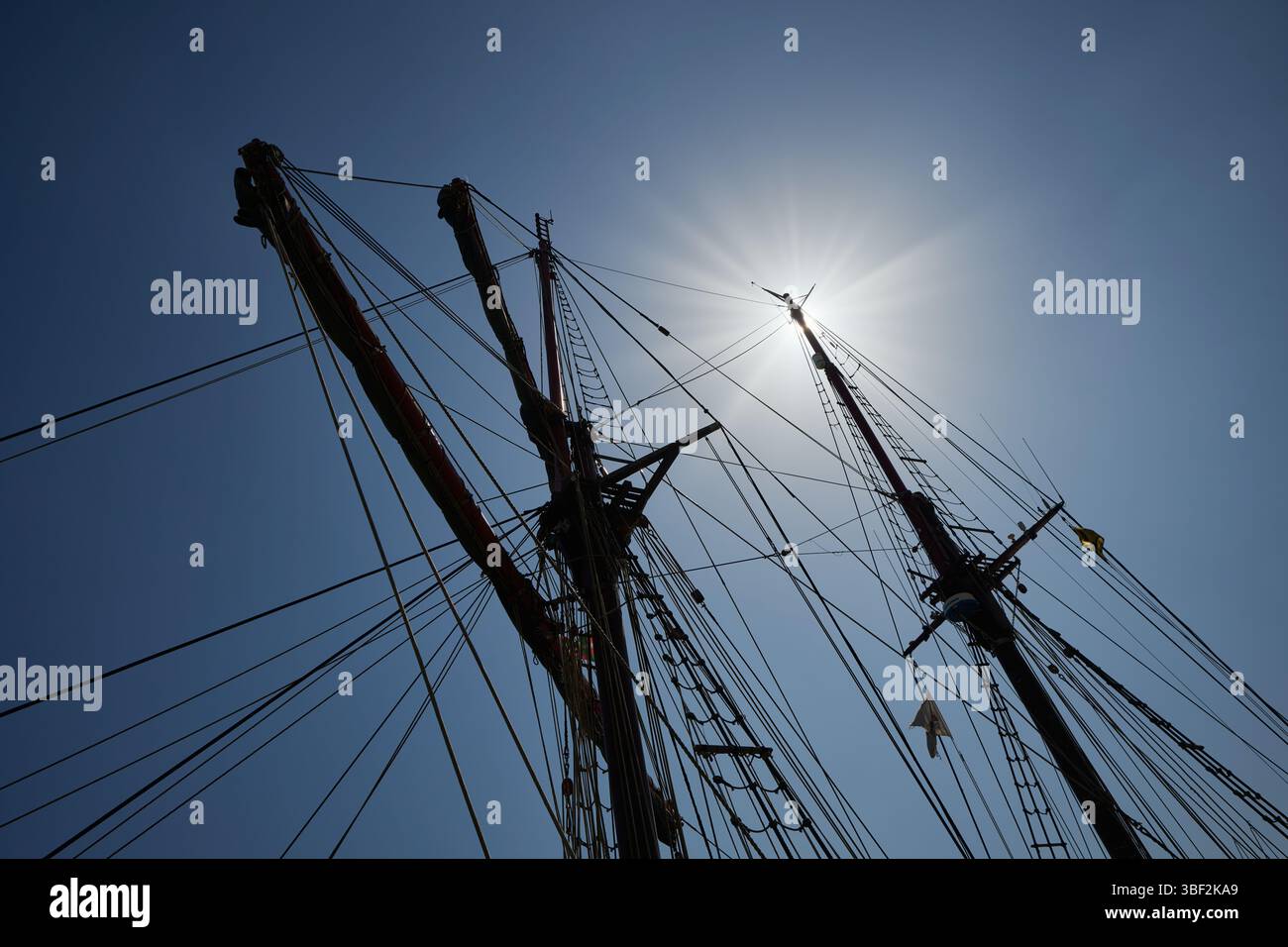 Two majestic sailing ship masts rise against a clear blue sky ...