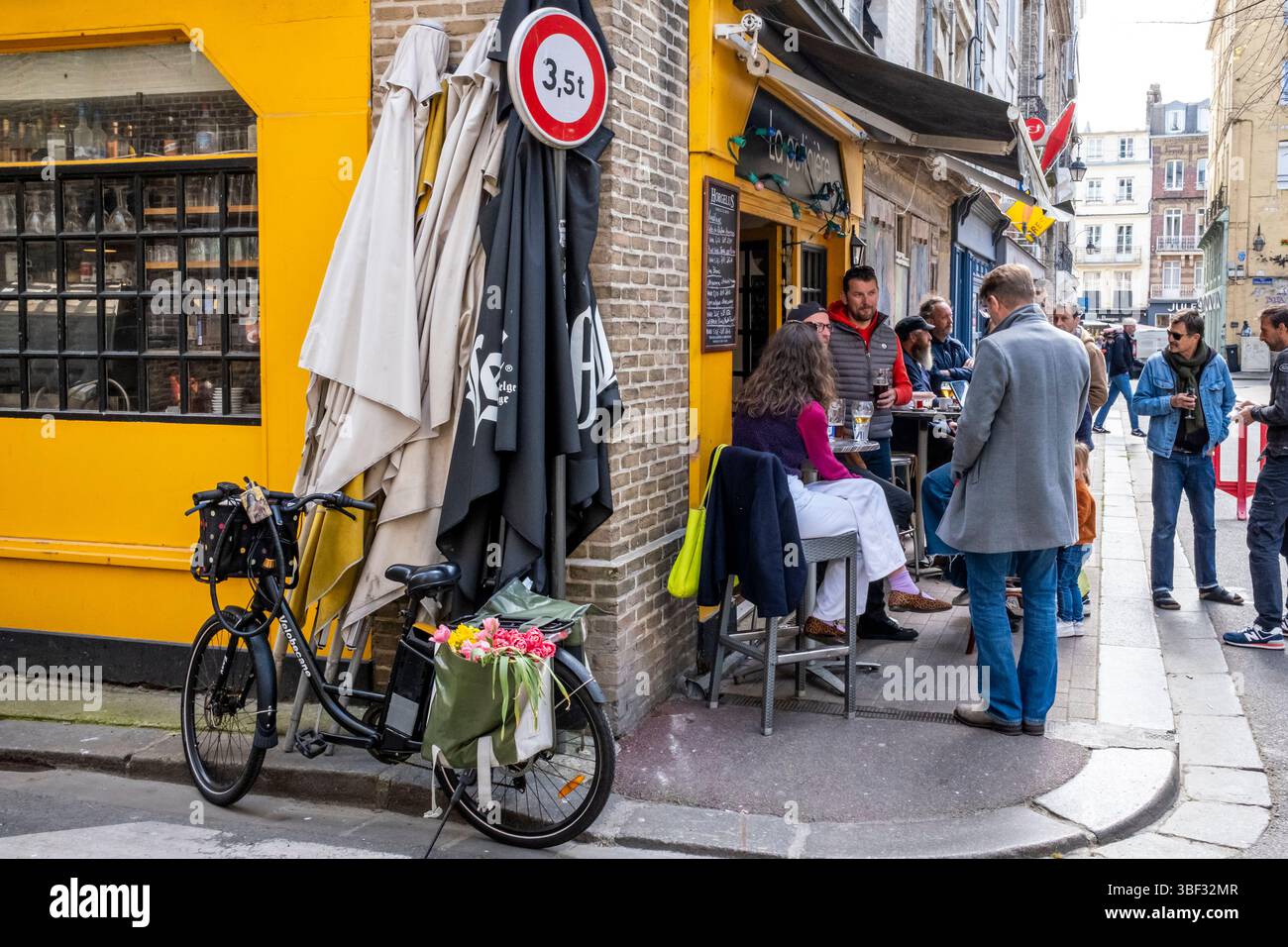 A Small Group Of People Sitting Down Outside A Cafe In The Town Of ...