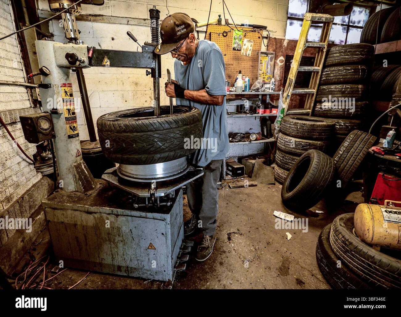 Reggie Osborne with Handyman and Sons Tire Shop works to dismount a ...