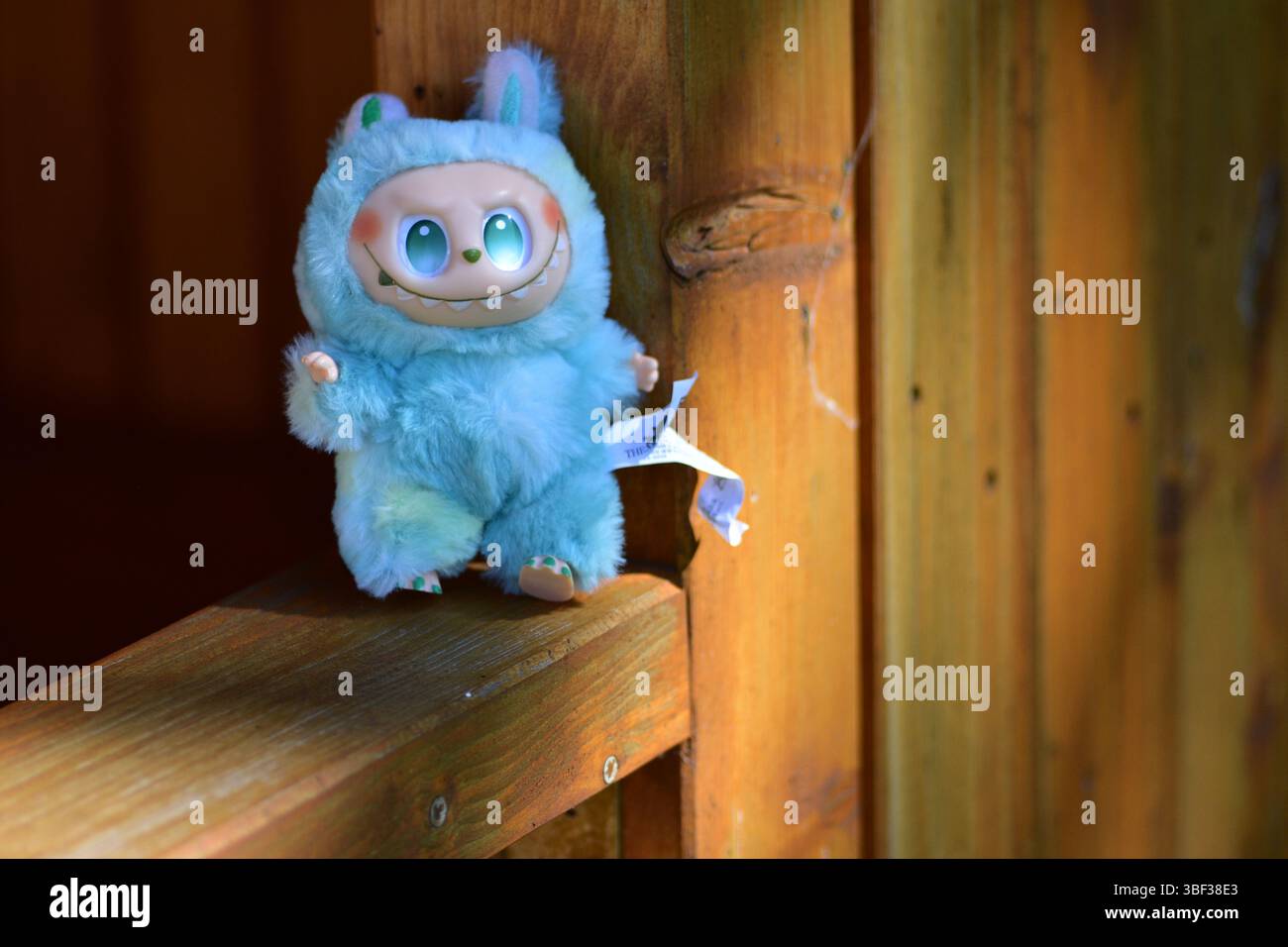 A playful Labubu toy figure in a fluffy blue monster costume with big ...