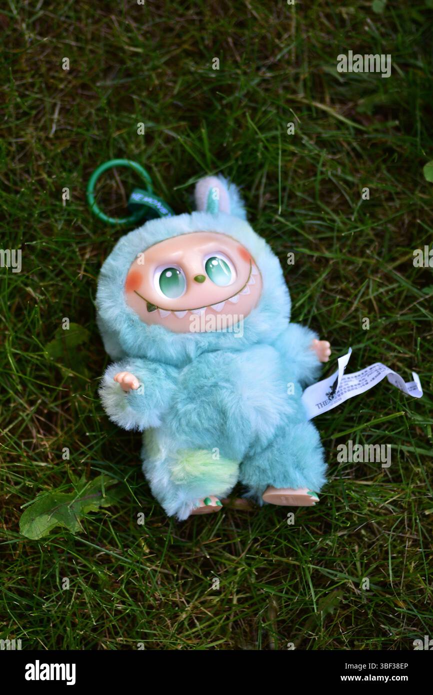 A playful Labubu toy figure in a fluffy blue monster costume with big ...