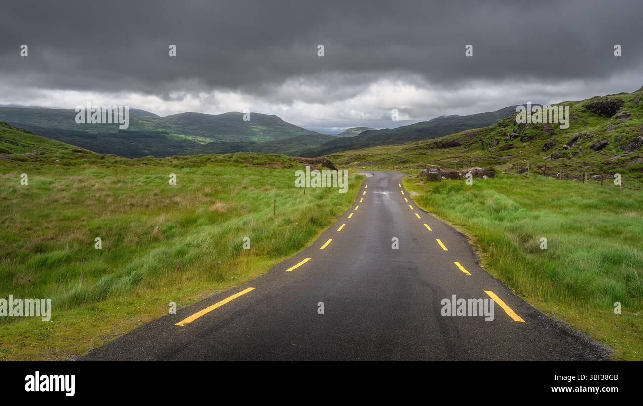A winding road meanders through colorful fields and gentle hills ...
