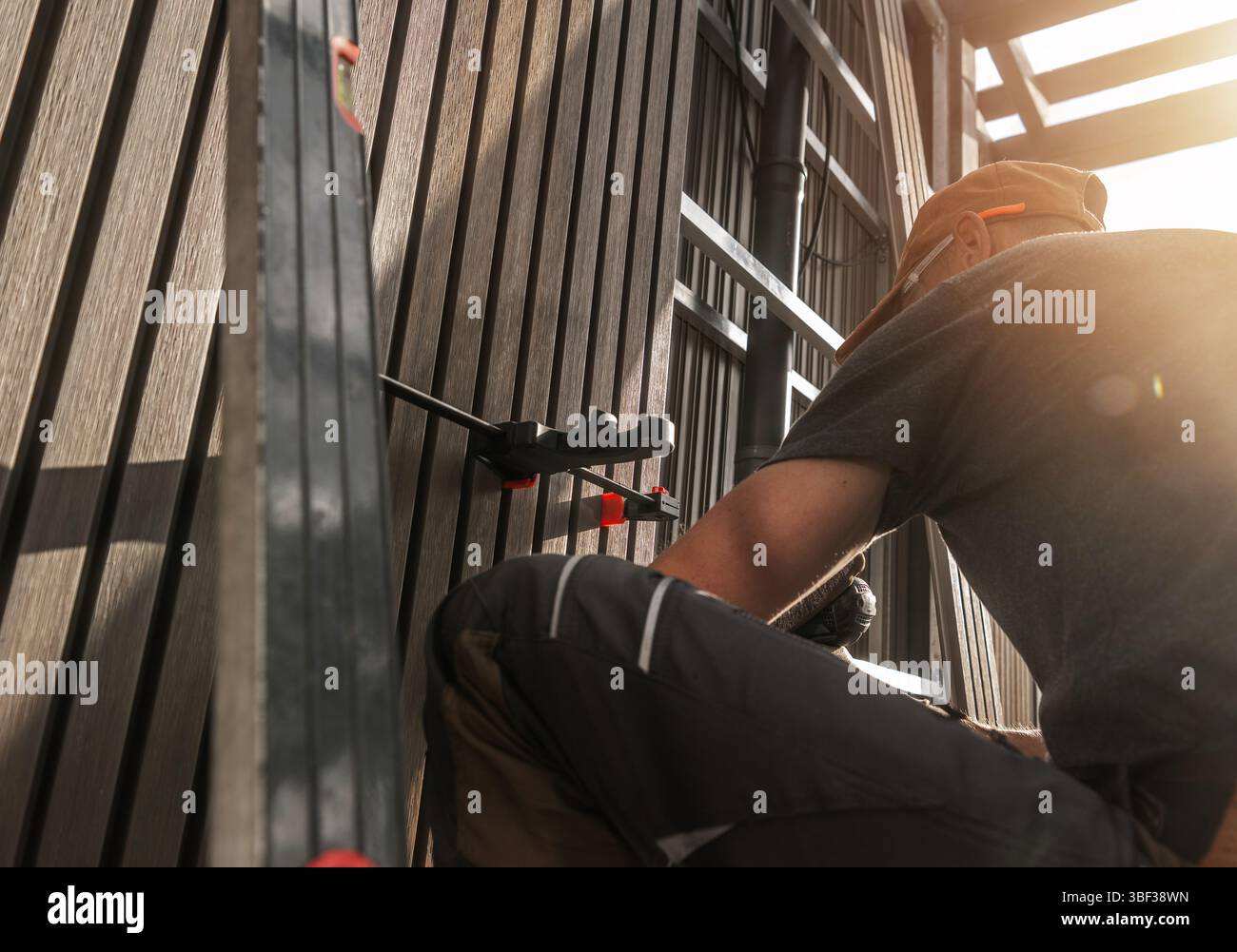 A dedicated craftsman focuses on installing wooden lamella slats in a ...