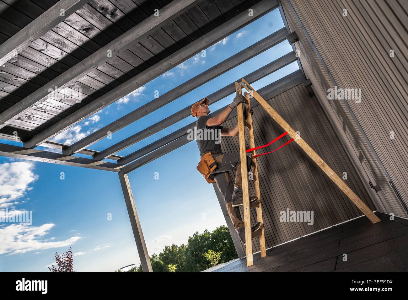 A worker is using a ladder to carefully install ceiling panels in a ...