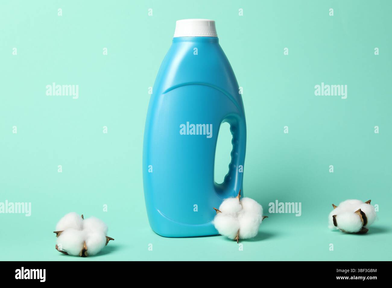 Bottle of fabric softener and cotton flowers on turquoise background ...