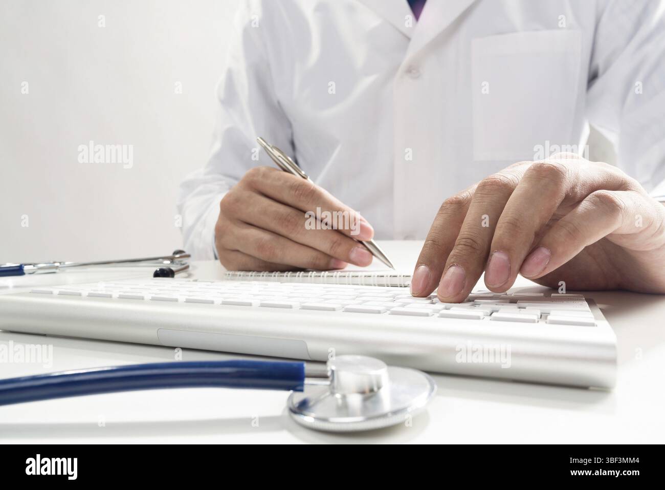 Doctor typing on wireless computer keyboard in office. Physician in ...