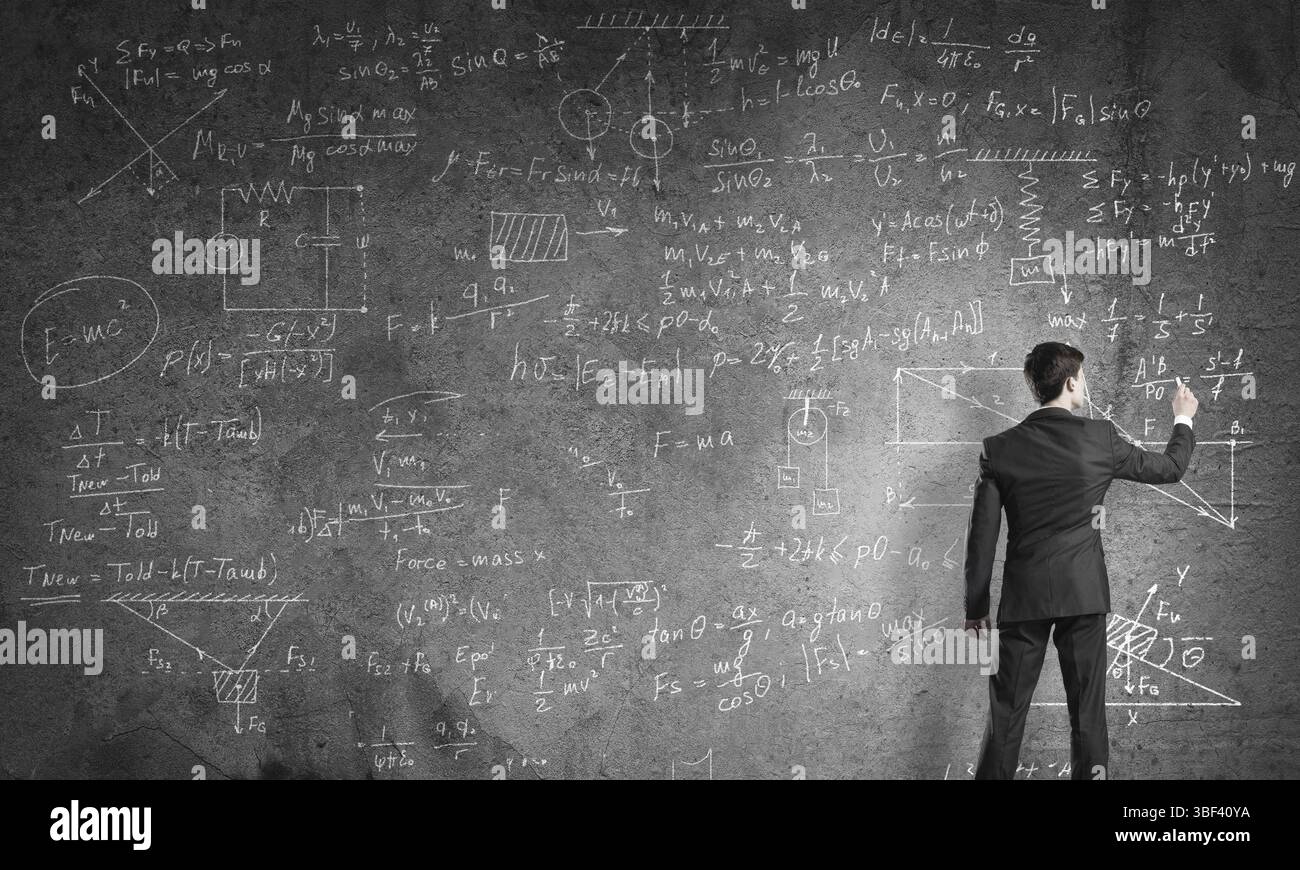 Man in suit standing with back and drawing physics formulas Stock Photo ...