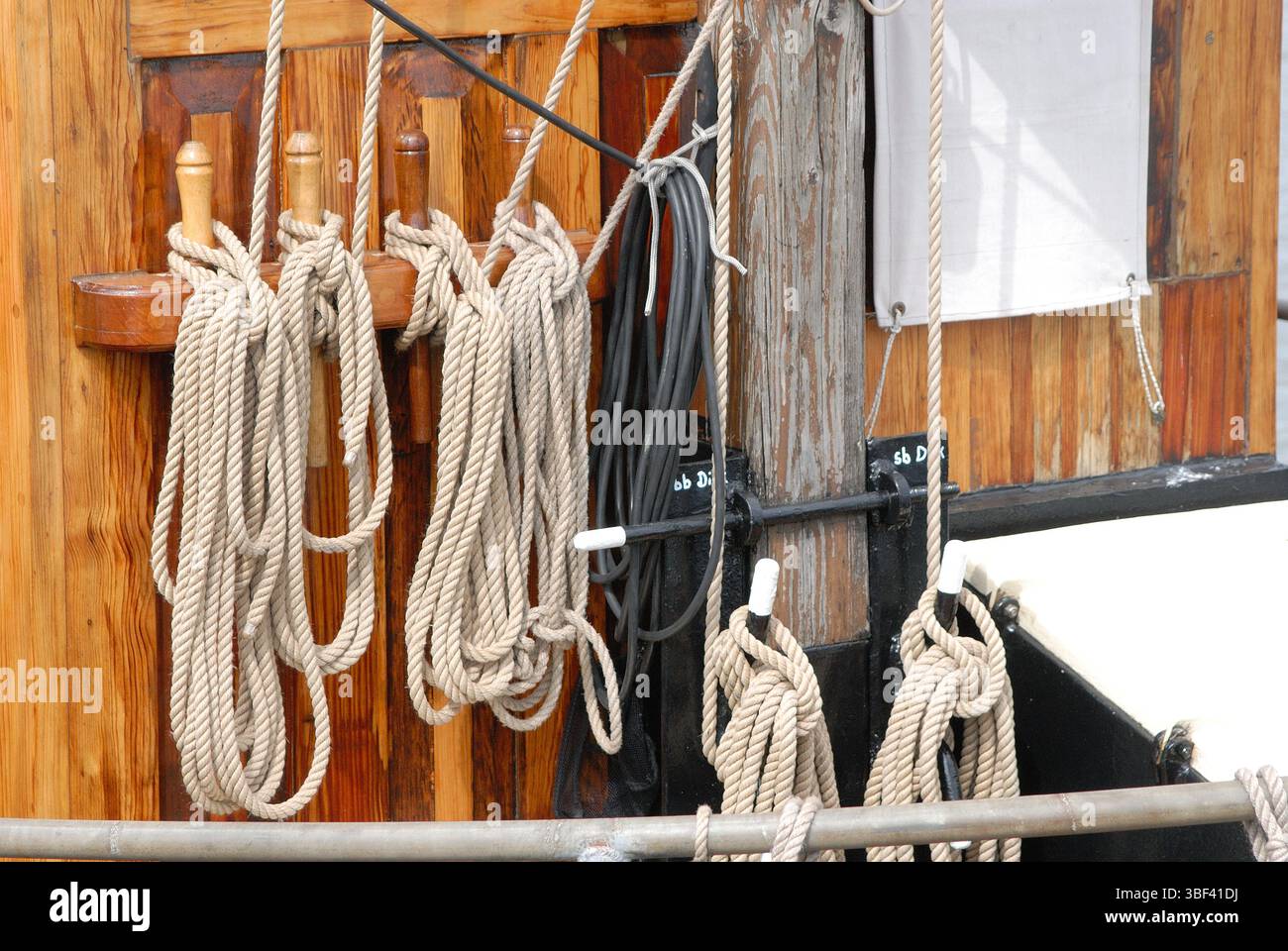 Neatly coiled natural fiber ropes hanging on wooden belaying pins and ...