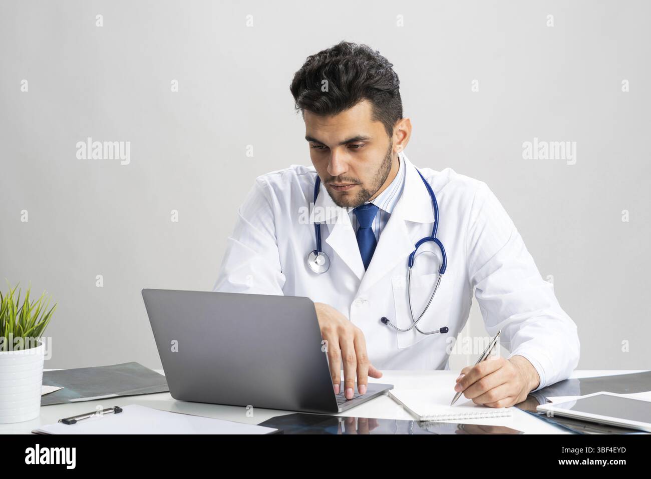 Handsome doctor sitting in office. Young practitioner in white coat ...