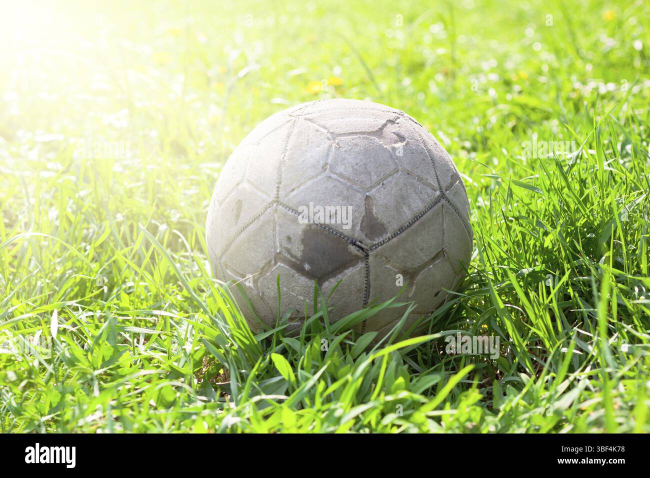 Old soccer ball forgotten in the green grass field. The football ...