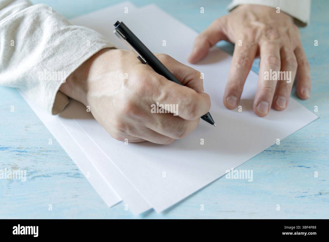 A pen in a man's hand. White sheet of paper. Signing a document Stock ...